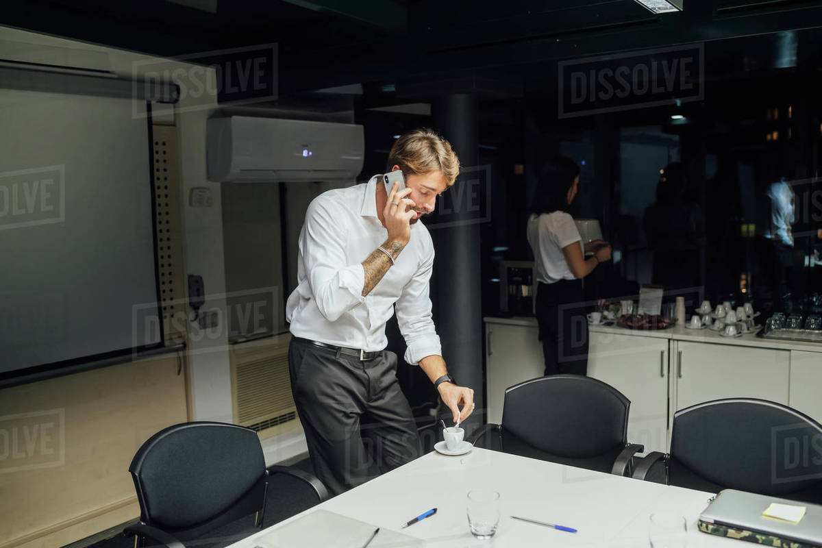 Businessman taking a break and making smartphone call in office ...