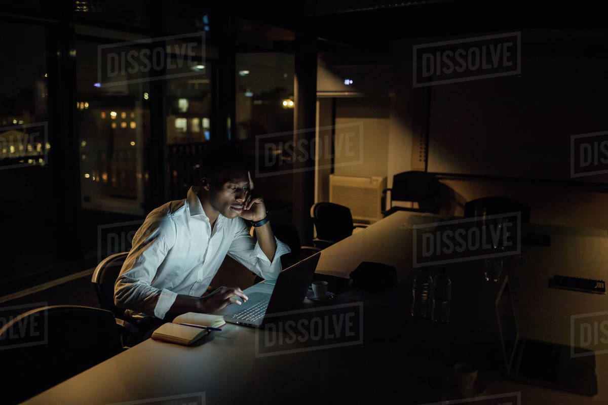 Tired young businessman in office at night typing on laptop - Stock ...