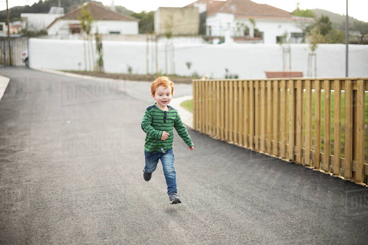 Boy running on road in residential area - Stock Photo - Dissolve