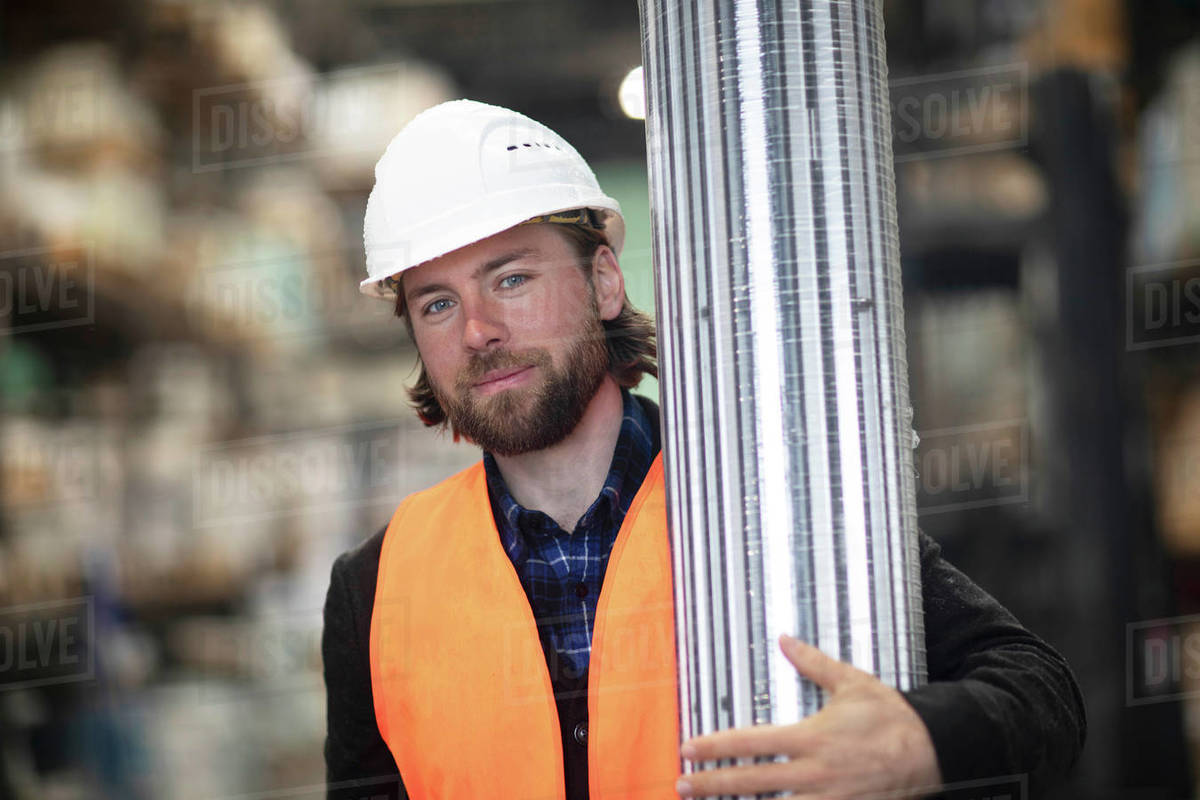 Mid adult male construction worker carrying building material on ...