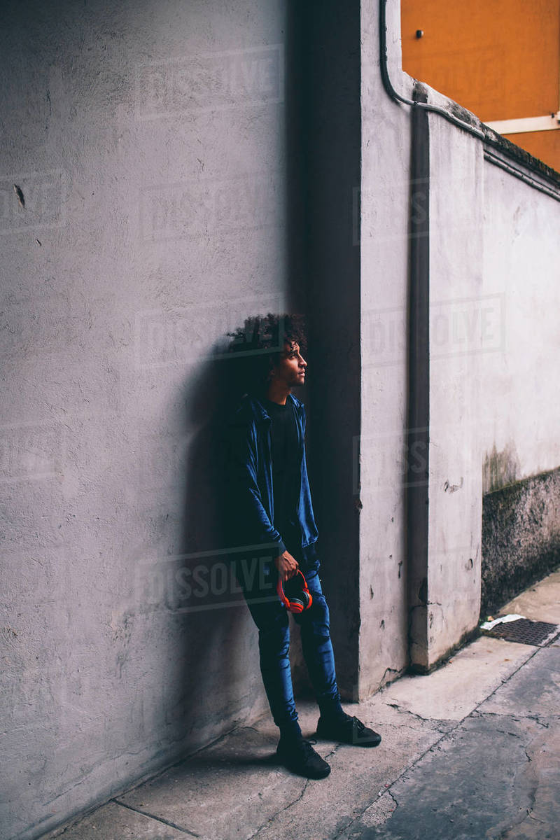 Young man waiting in front of concrete wall - Stock Photo - Dissolve