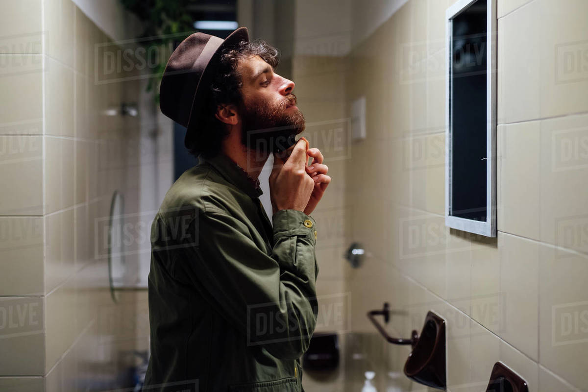 Bearded young man brushing beard in bathroom - Royalty-free Stock Photo ...