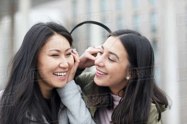 Friends sharing headphone, listening to music in city - Royalty-free ...