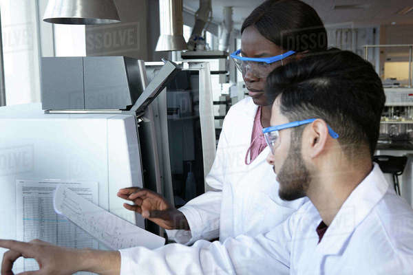 Young female and male scientists discussing paperwork in laboratory ...