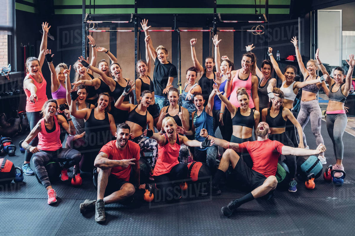 Large group of women training in gym with male trainers, posing for ...
