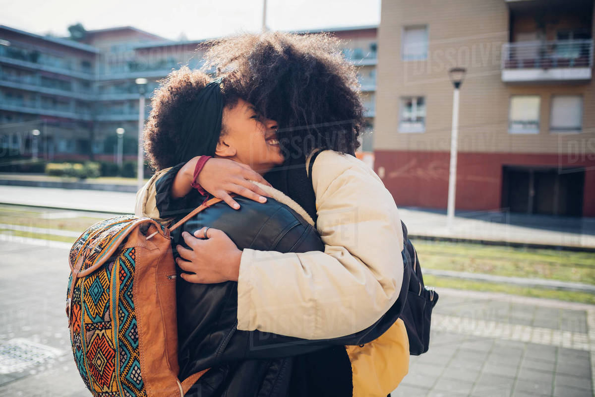 Two young women hugging on urban sidewalk - Royalty-free Stock Photo ...
