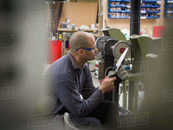 Knife factory worker examining knife blade in workshop - Stock Photo ...