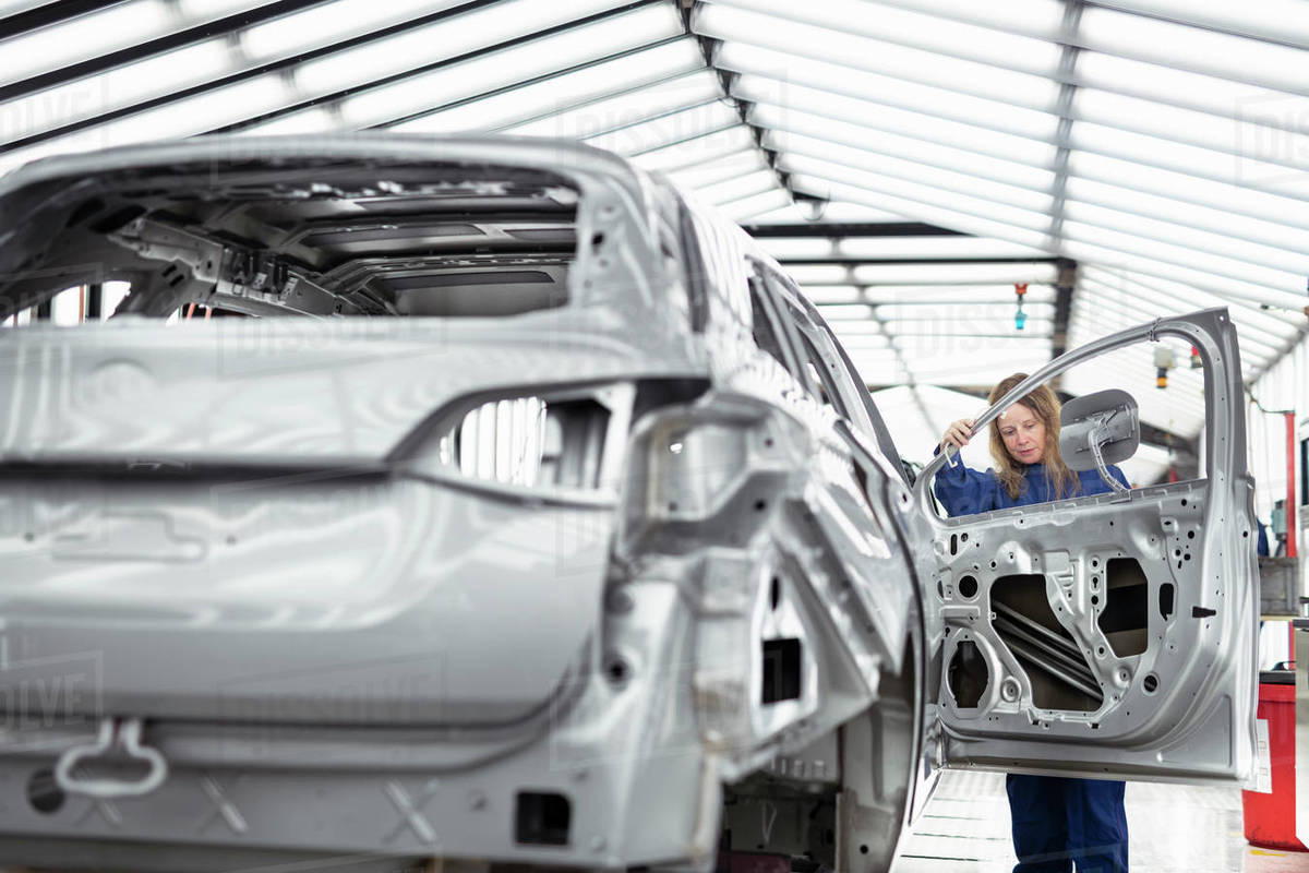 Worker inspecting car body in paint inspection area in car factory ...