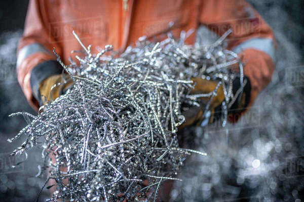 Close up of worker holding titanium swarf waste in titanium recycling ...