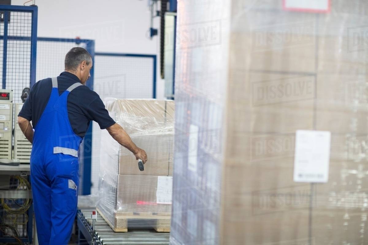 Worker using machine in paper packaging factory - Stock Photo - Dissolve