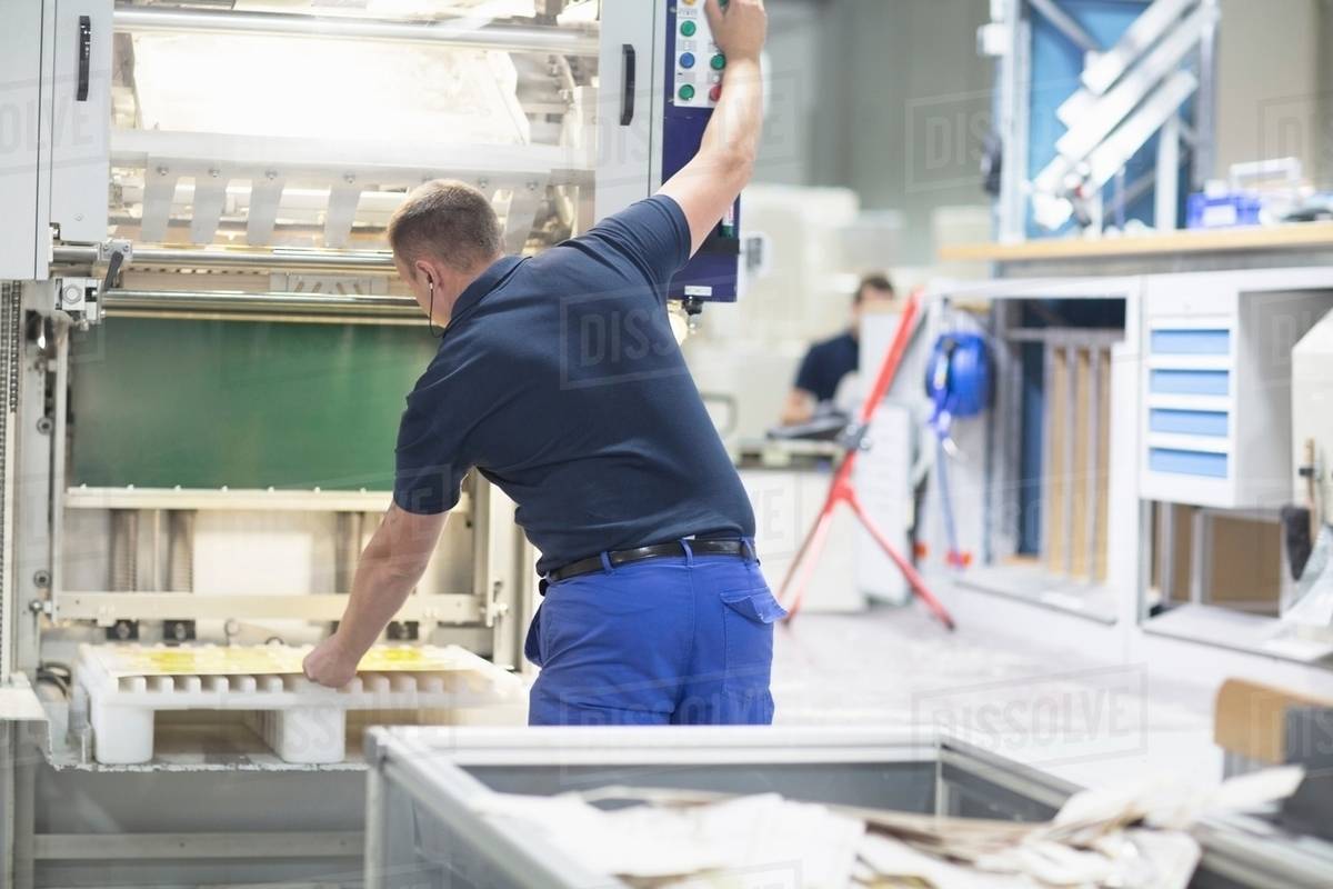 Worker using machine in paper packaging factory - Stock Photo - Dissolve