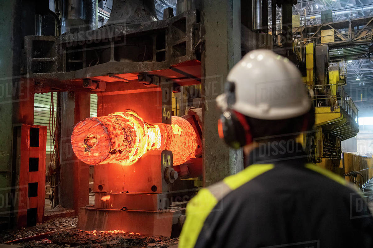 Red hot steel ingot in steel press in steelworks - Stock Photo - Dissolve