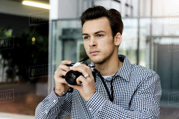 Portrait of young man with dark brown hair holding SLR camera. - Stock ...