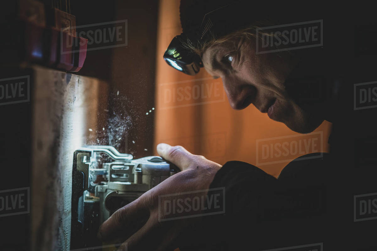 Close up of man wearing headlamp doing DIY. - Stock Photo - Dissolve