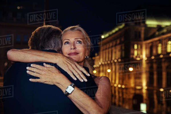 A woman hugging her partner and smiling over his shoulder during an ...
