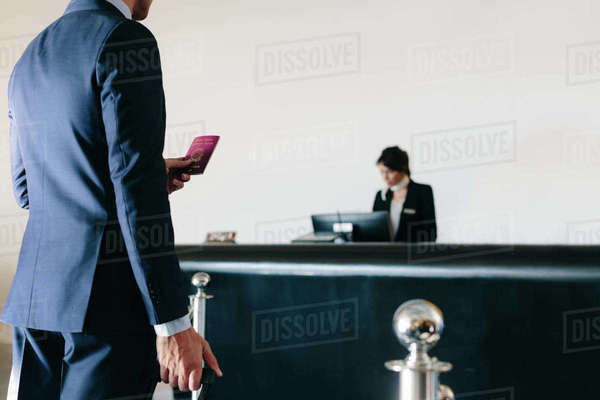 Businessman checking in at hotel reception - Stock Photo - Dissolve