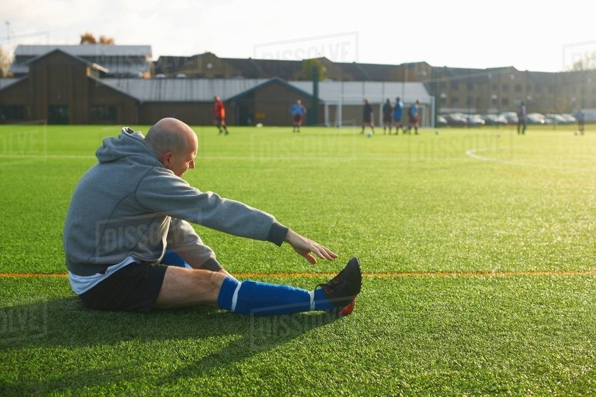 Football player stretching before game - Stock Photo - Dissolve