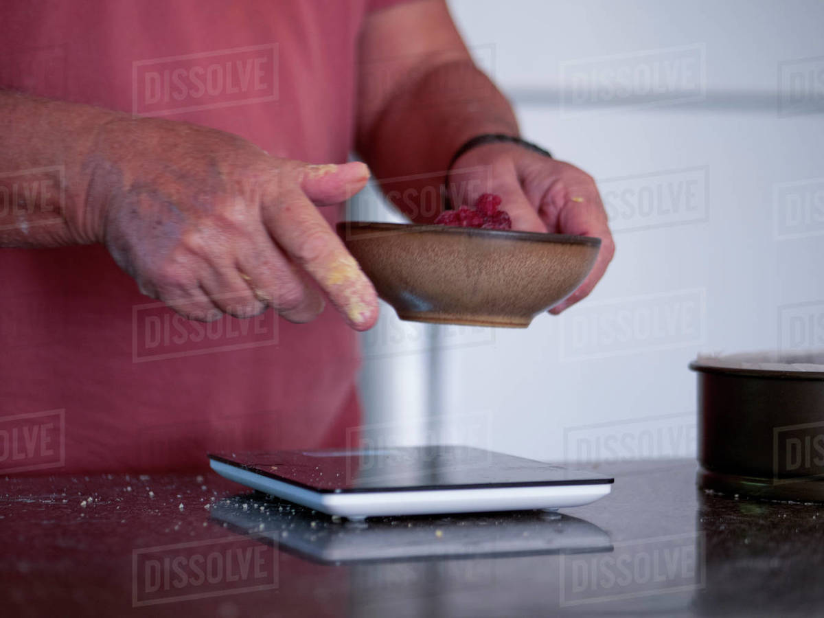 Man weighing ingredients for cake - Royalty-free Stock Photo | Dissolve