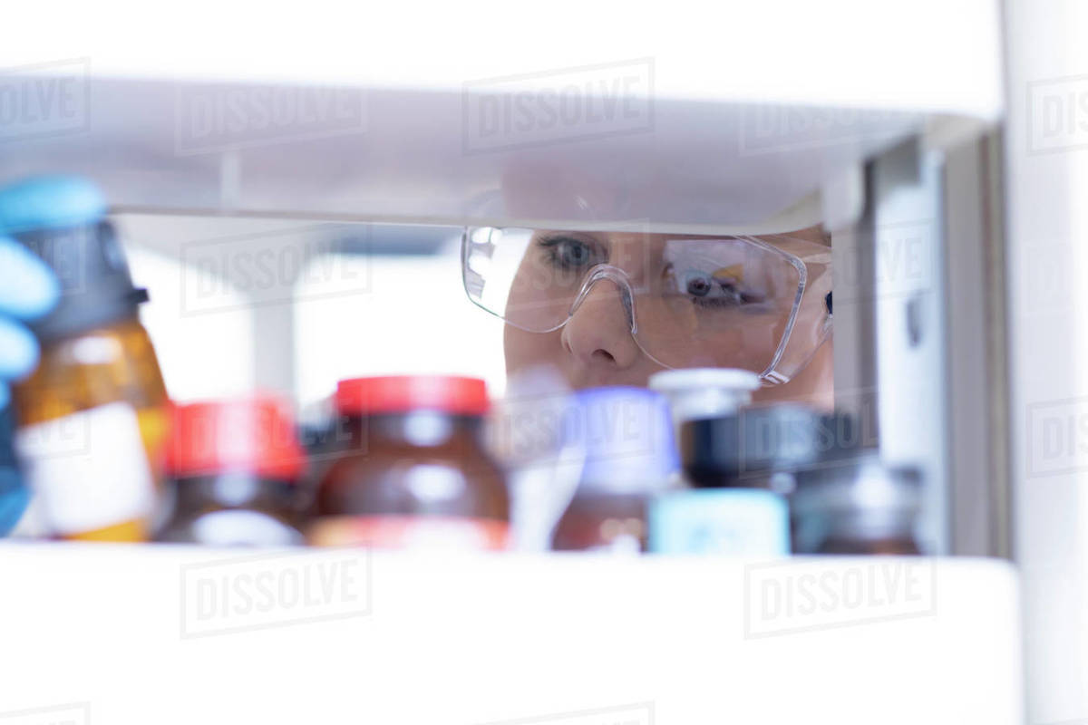 Curious scientist gazing at chemical samples in a laboratory fridge ...