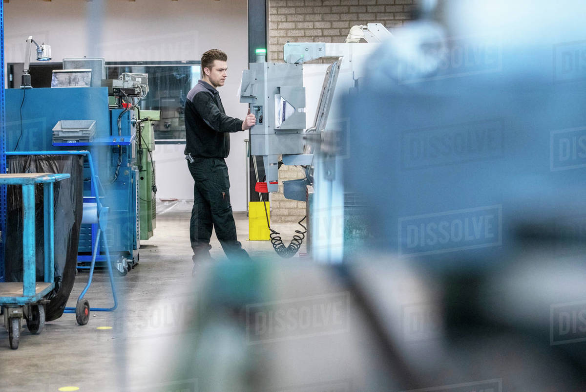 Young mechanical engineer working on steel machinery in a factory ...