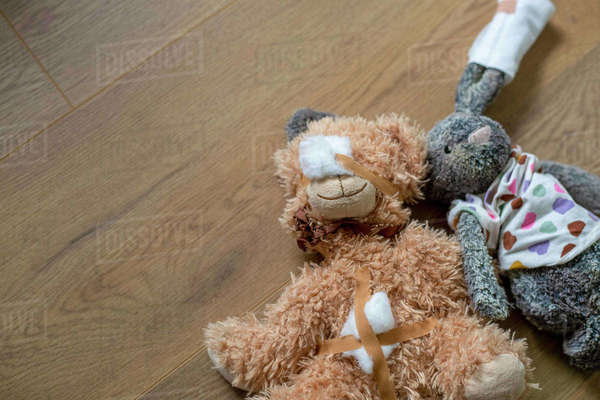 A child's cherished teddy bear and doll lying on a wooden floor - Stock ...