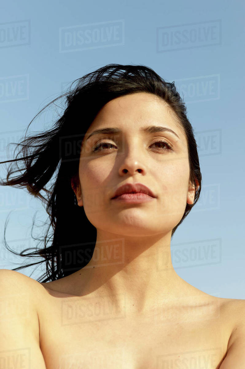 Woman with windblown hair stands in front of a scenic cityscape on a ...