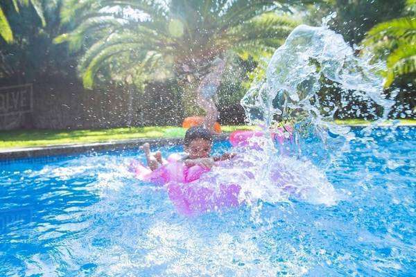 Girl and boy splashing around in garden swimming pool - Royalty-free ...