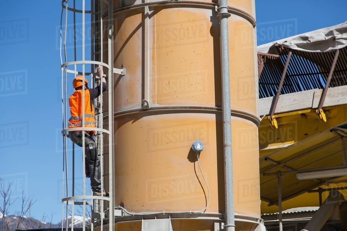 Quarry worker climbing smoke stack ladder at gravel quarry - Stock ...