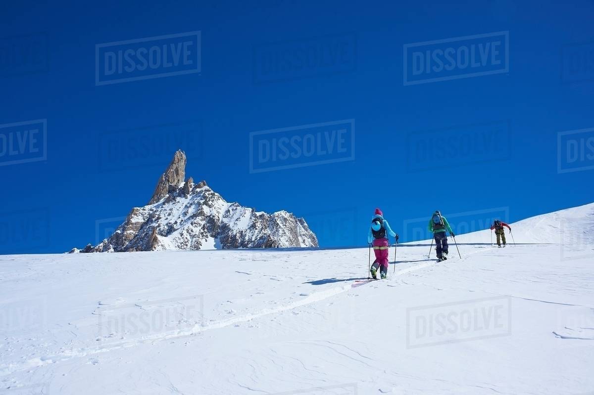 Rear view of three skiers moving up Mont Blanc massif, Graian Alps ...