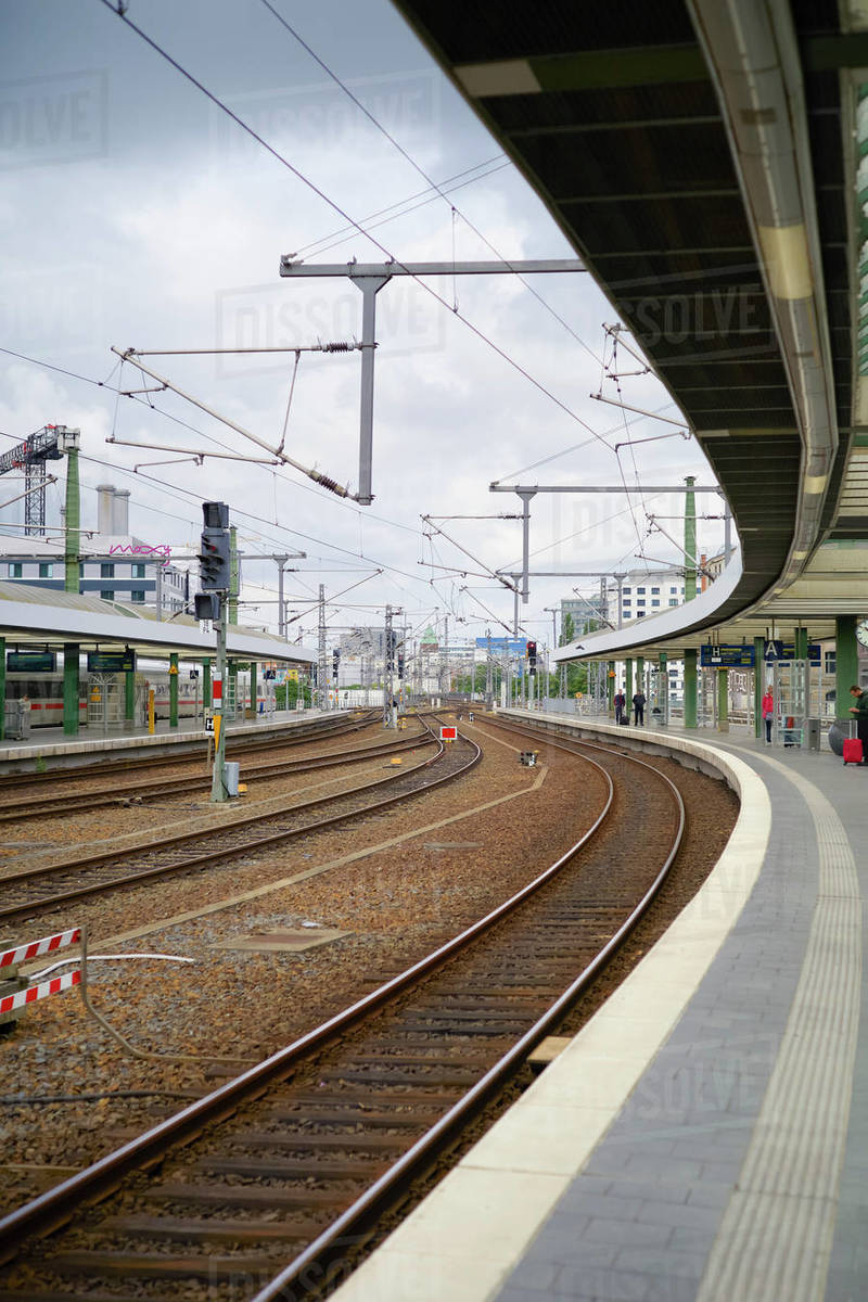 Empty train station platform with railway tracks curving into the ...