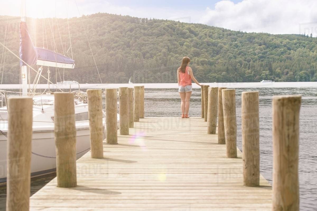 Young woman standing on jetty looking over lake on sunny day - Royalty ...