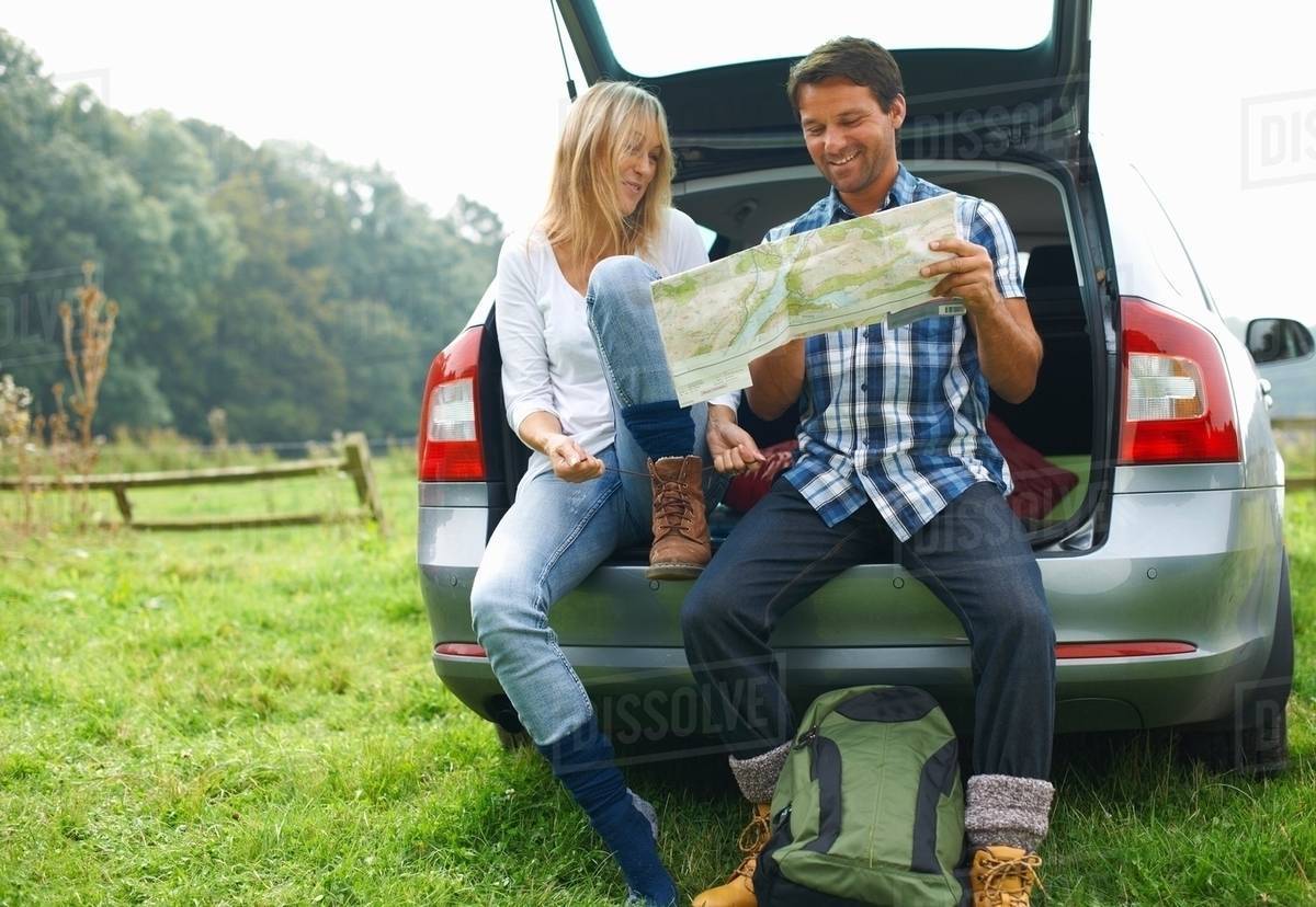 Couple at rear of car map reading preparing for walk - Royalty-free ...