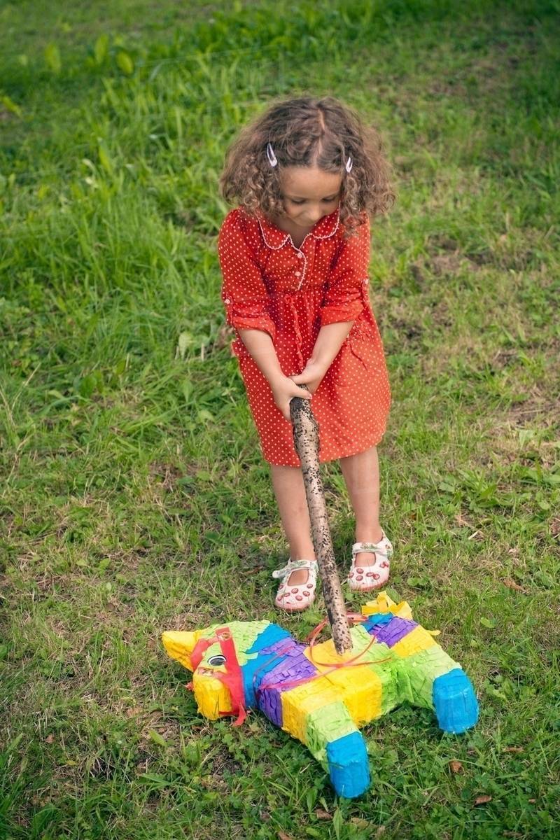 Girl opening pinata on ground at party - Stock Photo - Dissolve