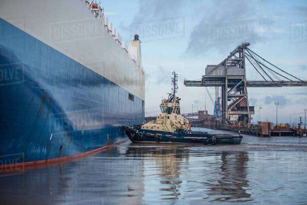 Tug pushing ship in port - Stock Photo - Dissolve