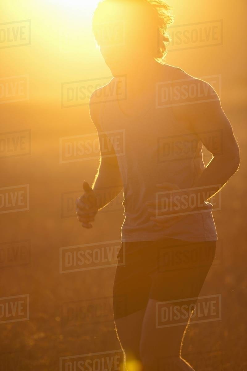 Man running in tall grass at sunset - Royalty-free Stock Photo | Dissolve