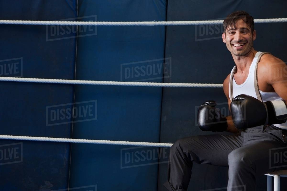 Smiling boxer sitting in ring - Stock Photo - Dissolve