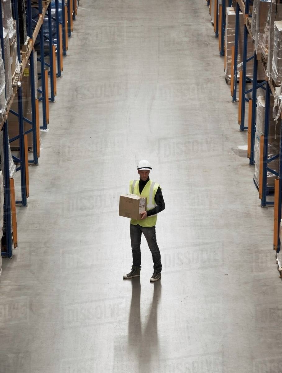 Worker carrying box in warehouse - Royalty-free Stock Photo | Dissolve