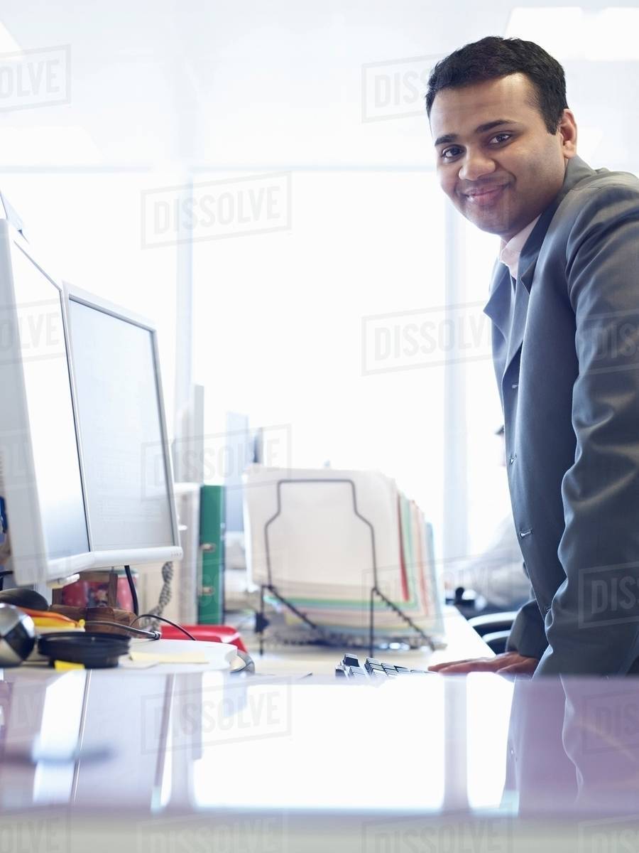 Businessman smiling at desk - Stock Photo - Dissolve