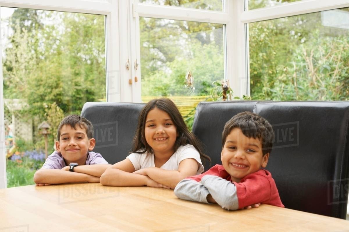 Children smiling at table - Stock Photo - Dissolve