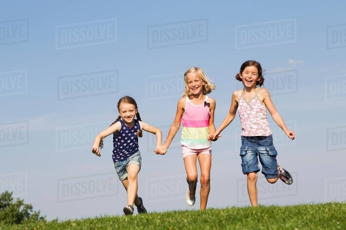 Girls running together in field - Royalty-free Stock Photo | Dissolve
