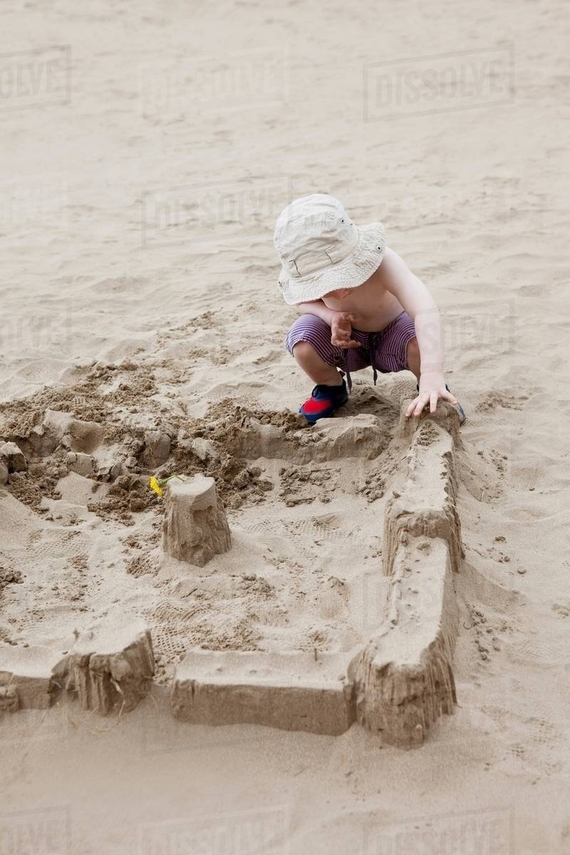 Boy building sandcastle on beach - Royalty-free Stock Photo | Dissolve