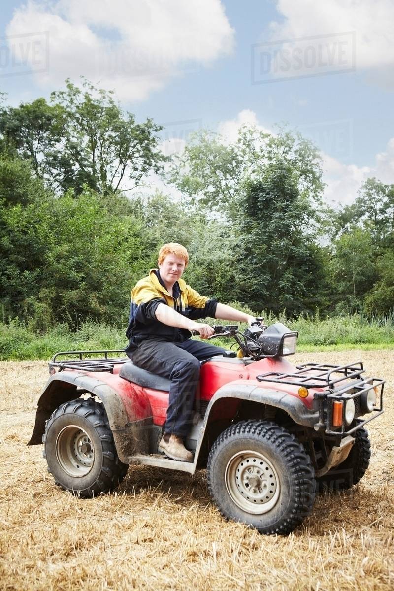 Worker driving four wheeler in field - Stock Photo - Dissolve