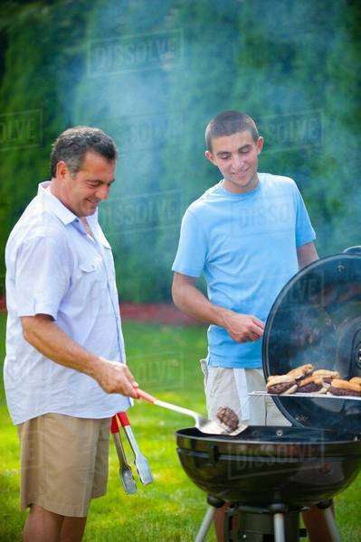Father and son grilling outdoors - Stock Photo - Dissolve
