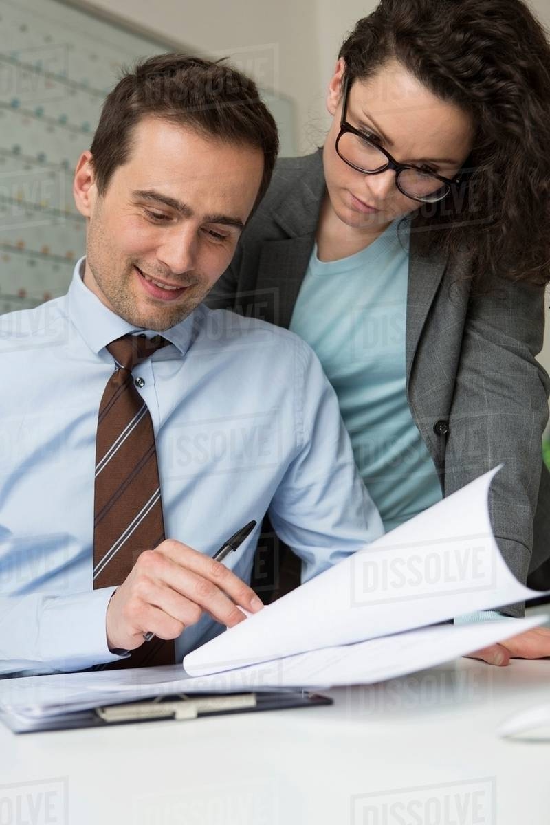 Businesspeople smiling looking at paperwork - Stock Photo - Dissolve