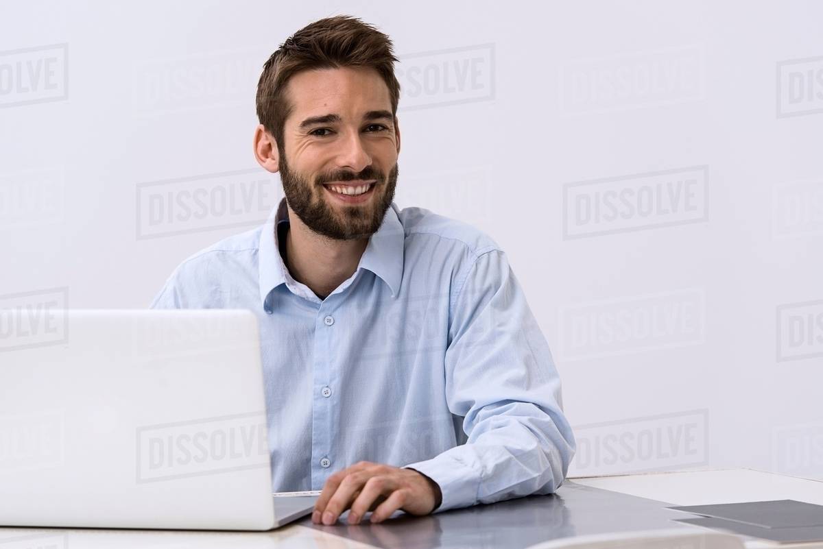 Portrait of young man sitting at desk with laptop - Royalty-free Stock ...