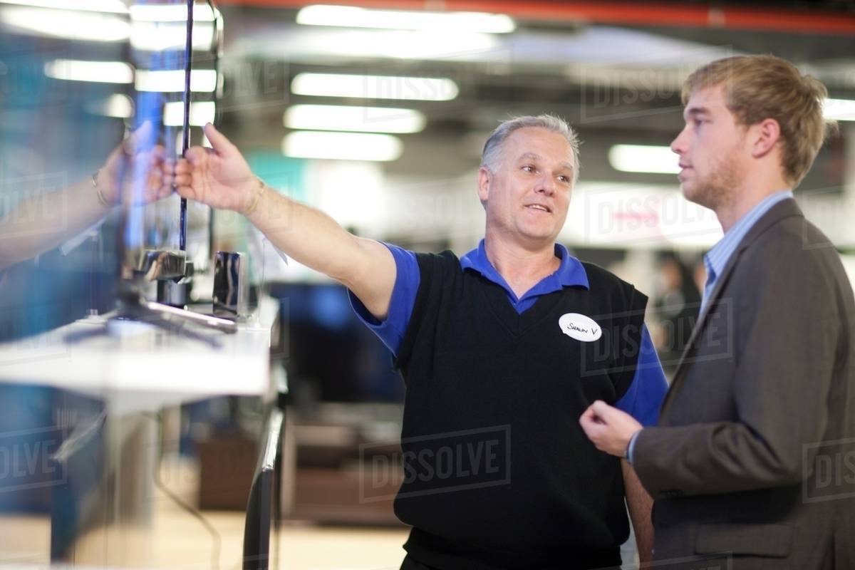Young man looking at flat screen TV in showroom - Stock Photo - Dissolve