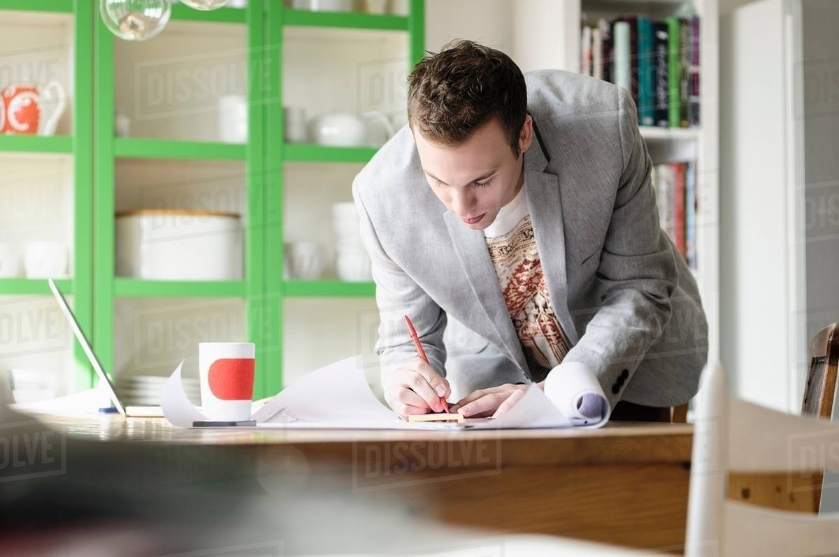 Man bending over work documents - Stock Photo - Dissolve
