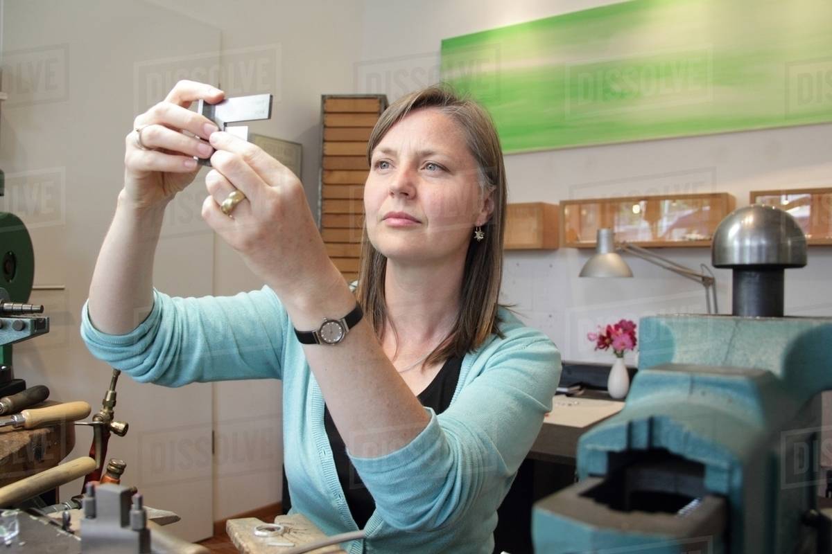 Female goldsmith taking measurements in workshop - Stock Photo - Dissolve