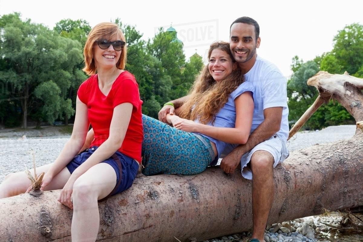Three friends sitting on log - Royalty-free Stock Photo | Dissolve