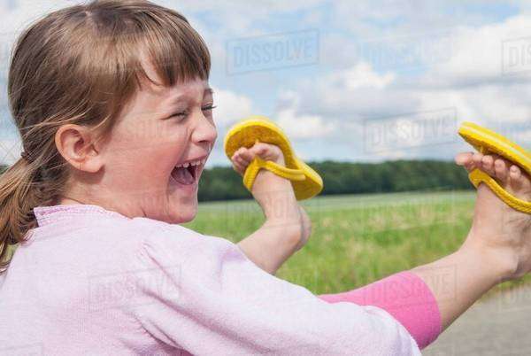 Girl wearing flip flops laughing - Royalty-free Stock Photo | Dissolve
